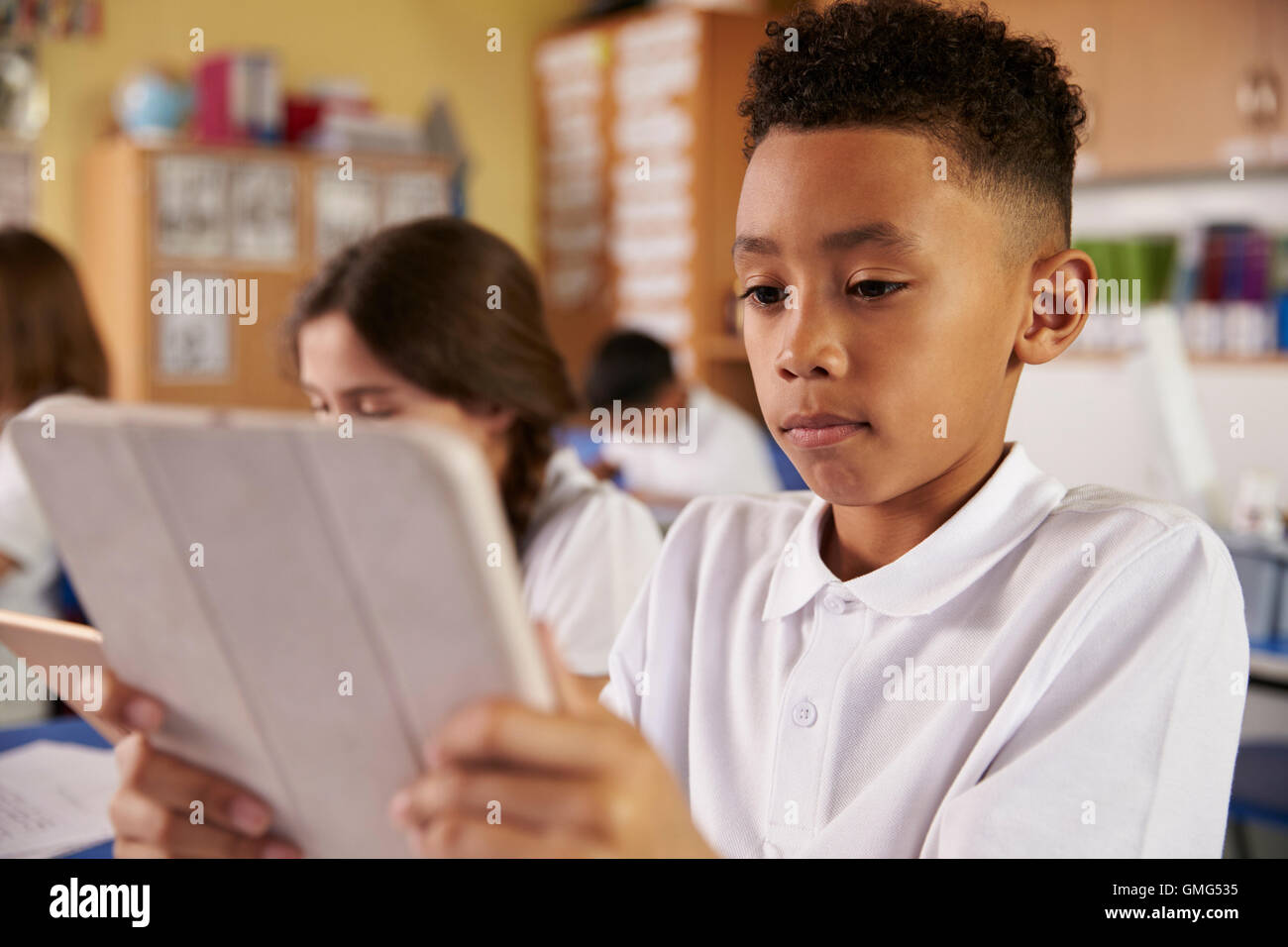 Mixed race primary school boy using tablet computer in class Stock ...