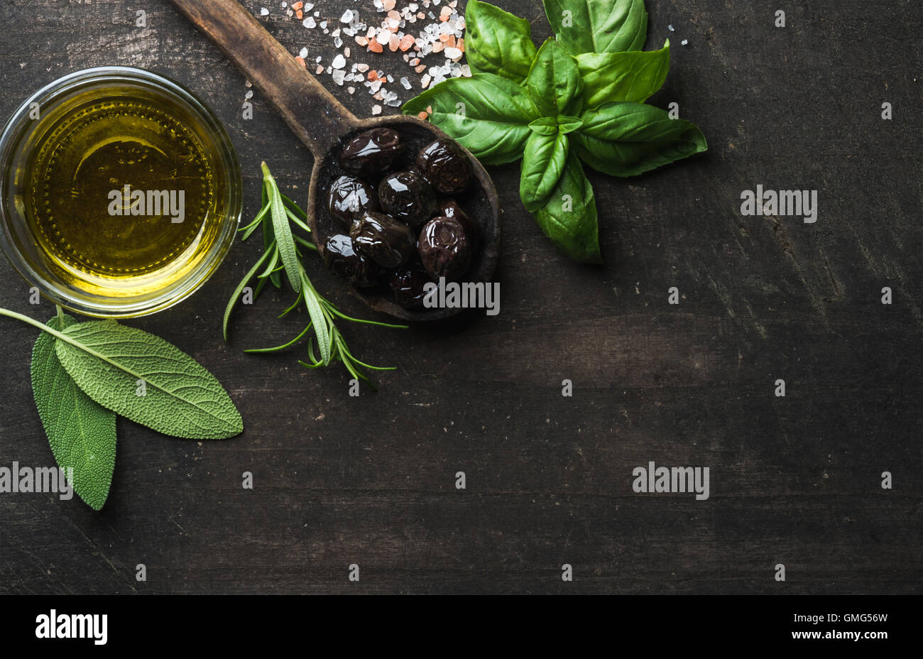 Greek black olives, fresh herbs and oil on dark rustic wooden ...