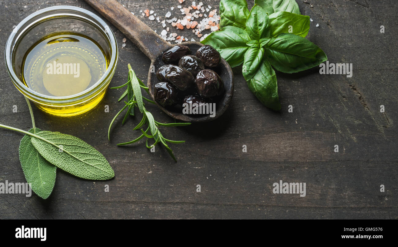 Greek black olives, fresh herbs and oil on dark rustic wooden ...