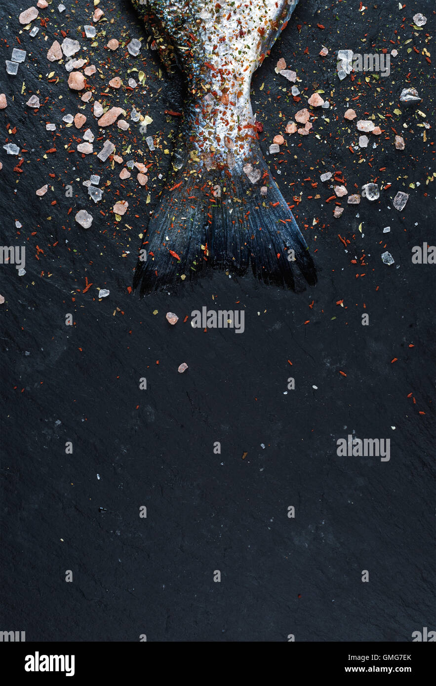 Tail of fresh raw Dorado or sea bream fish on black slate stone board ...