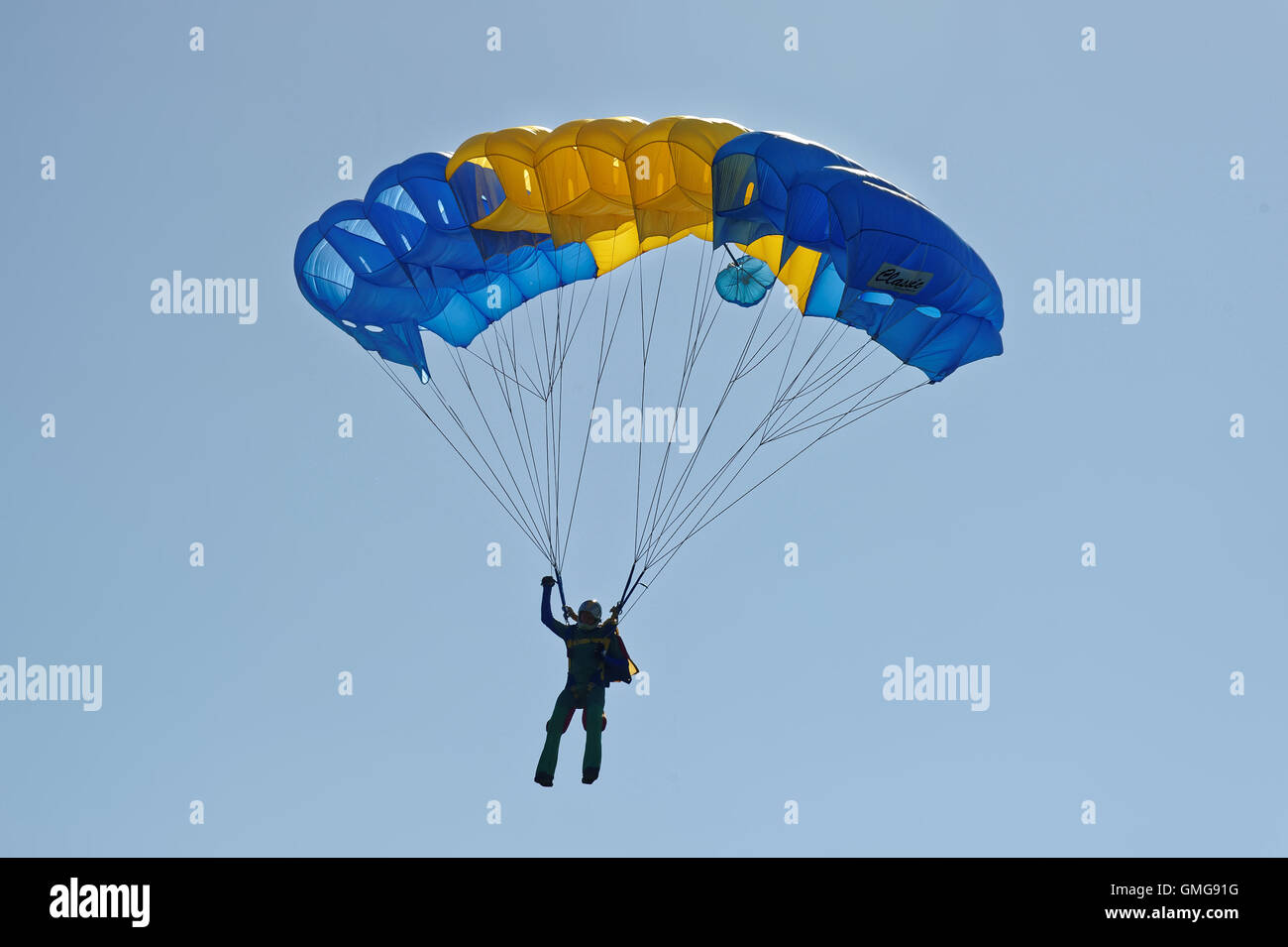 Paraglider flying on colorful parachute in blue clear sky at a bright ...