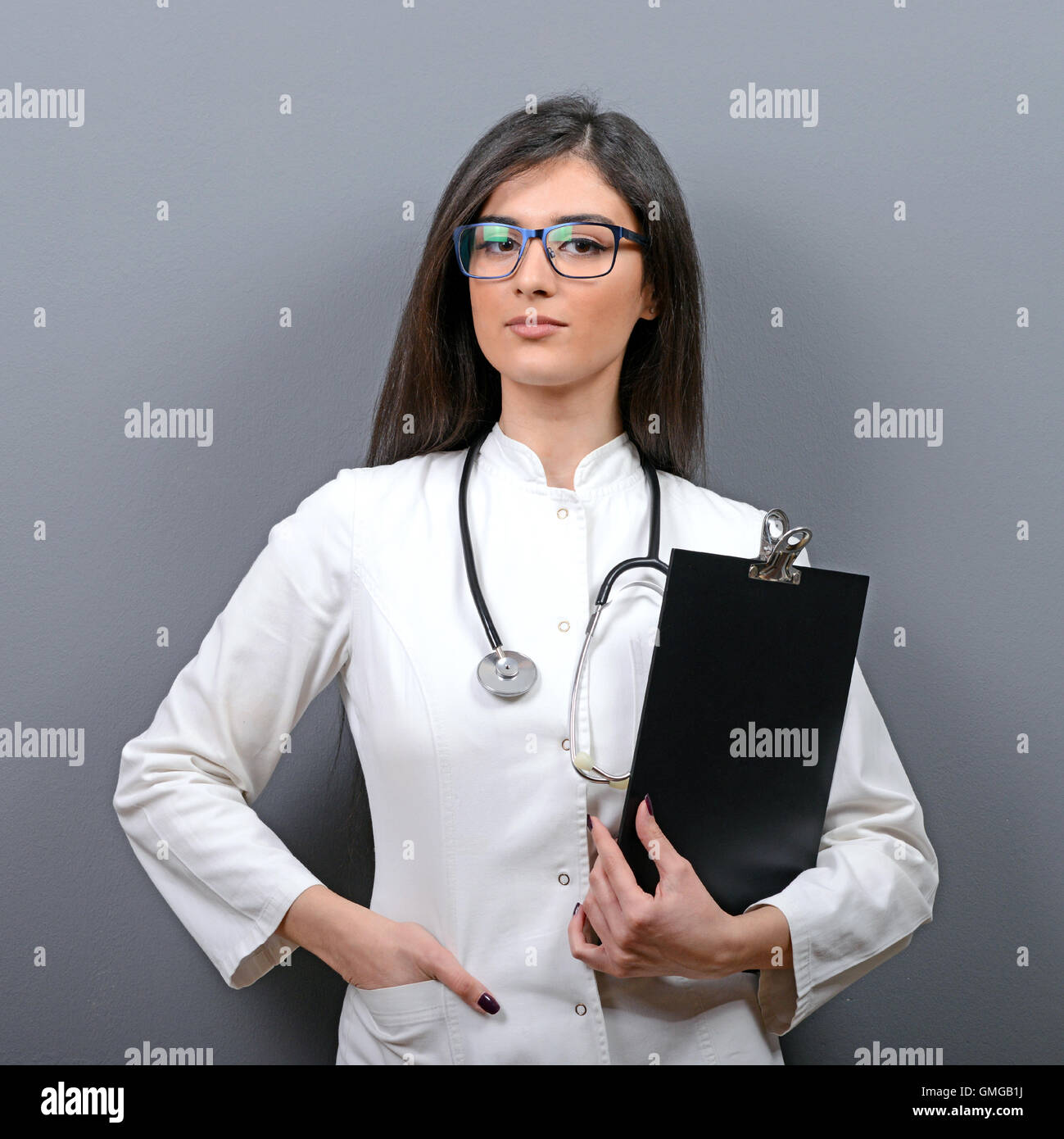 Portrait of confident medical doctor woman holding clipboard against ... Portrait of confident medical doctor woman holding clipboard against ...