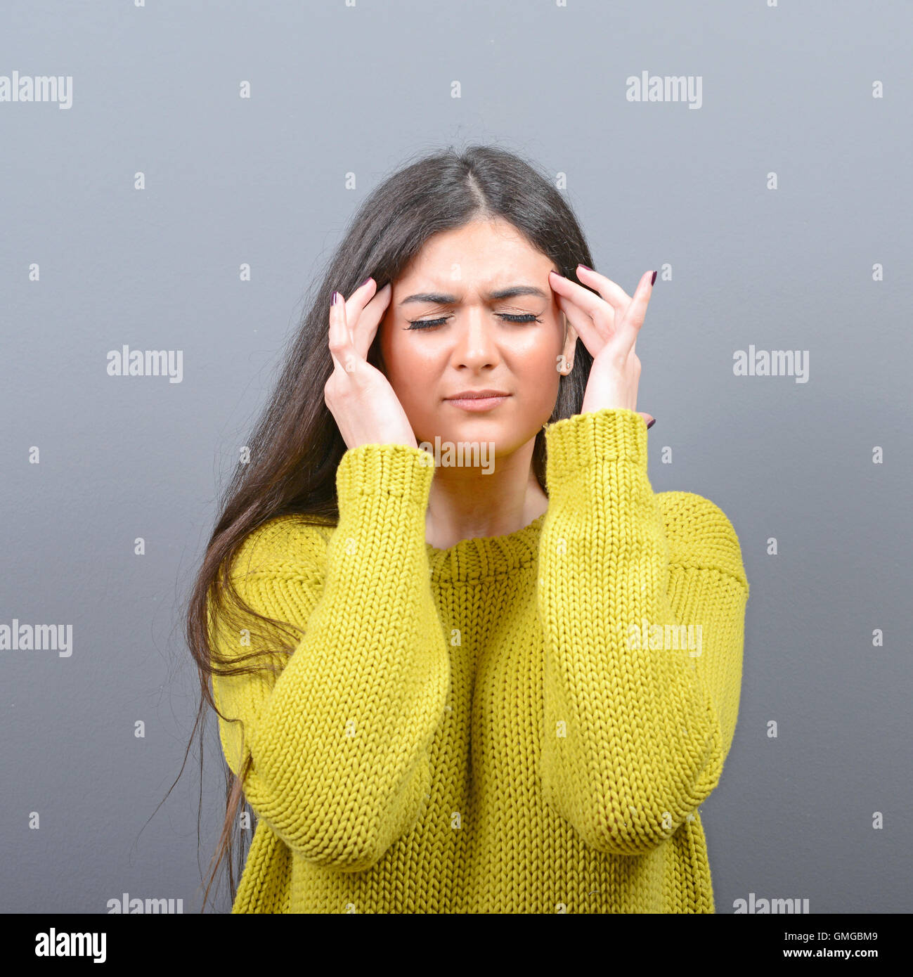Portrait of woman with headache against gray background Stock Photo - Alamy