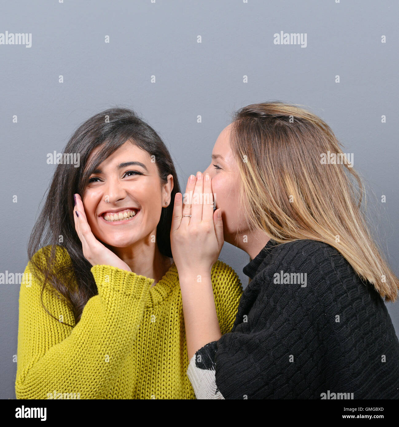Two woman friends whispering secrets against gray background Stock ...