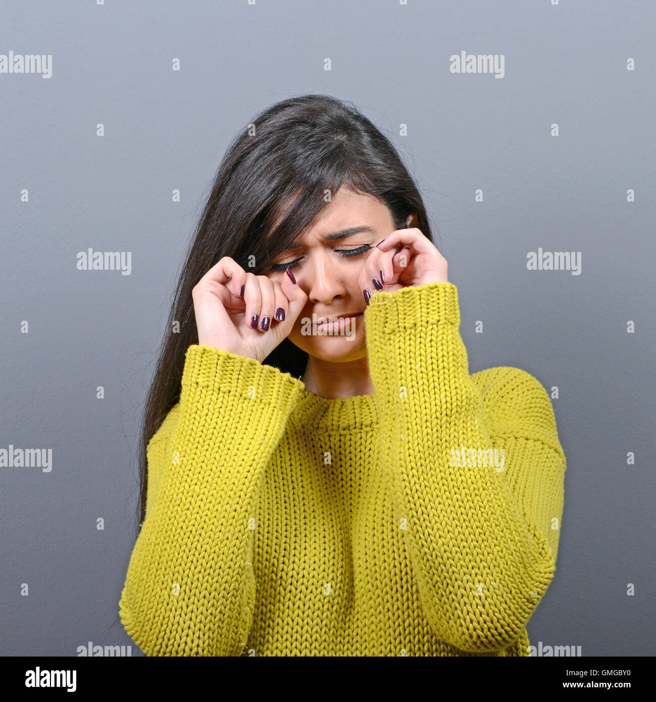 Woman crying and wiping tears against gray background Stock Photo - Alamy