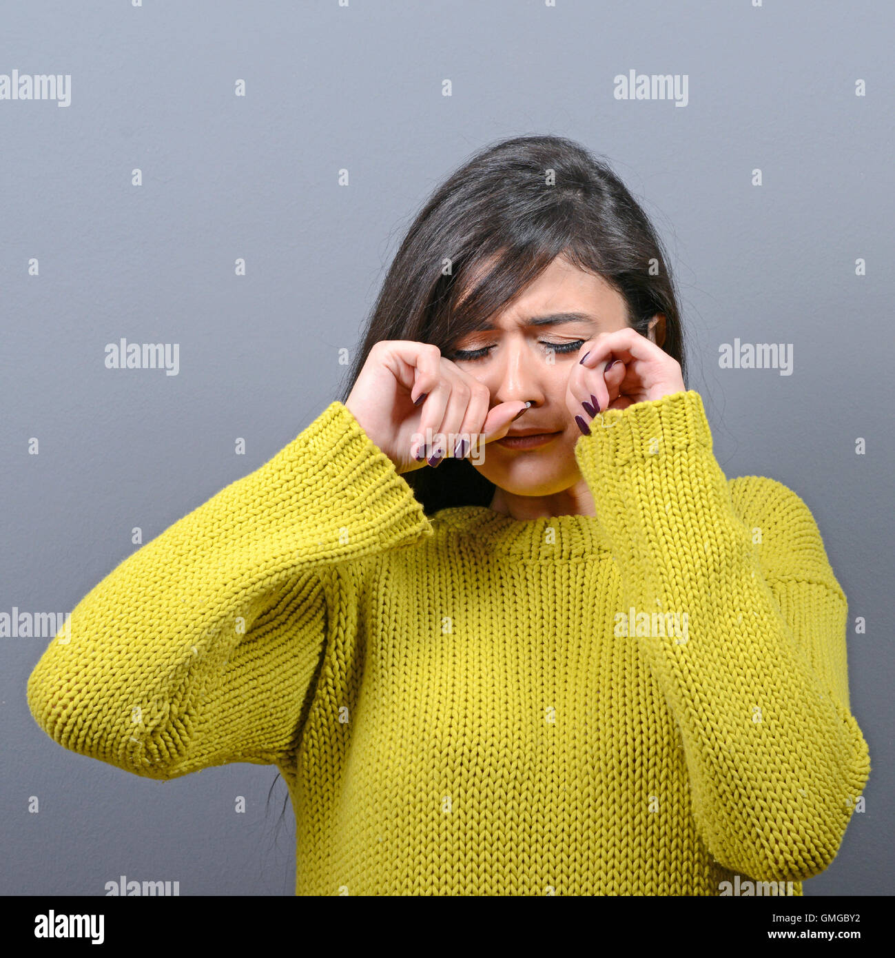 Woman crying and wiping tears against gray background Stock Photo - Alamy