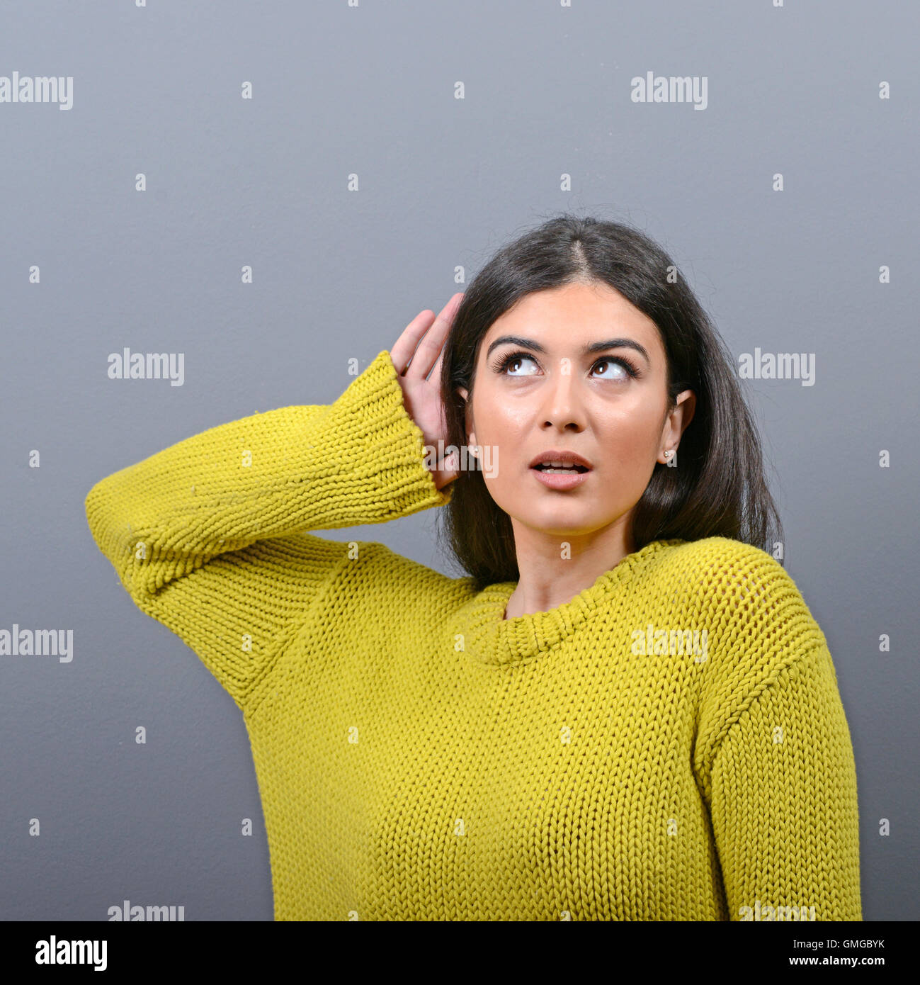 Woman listening with hand to ear concept against gray background Stock ...