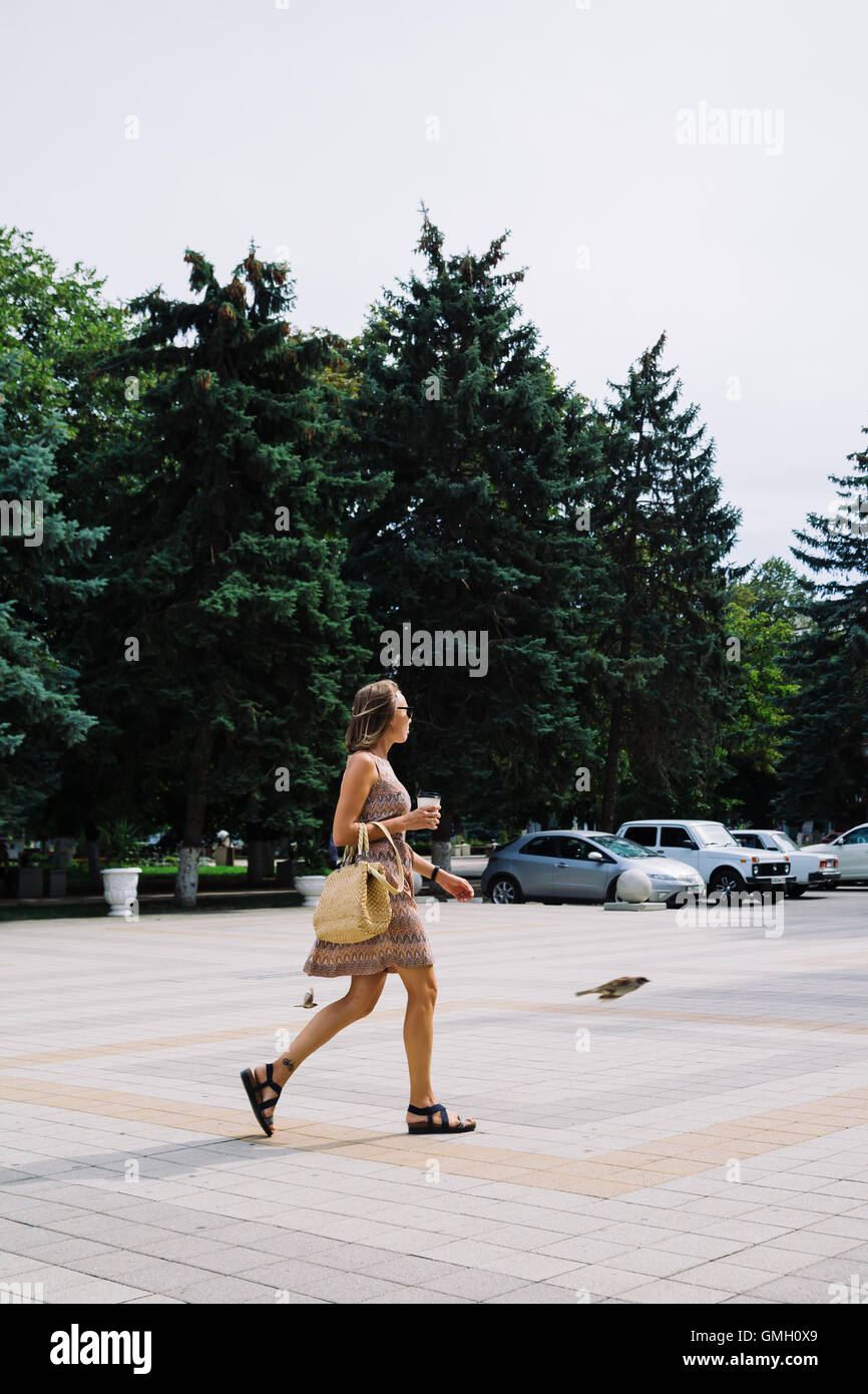 Young brunette woman with coffee cup walking in city Stock Photo - Alamy