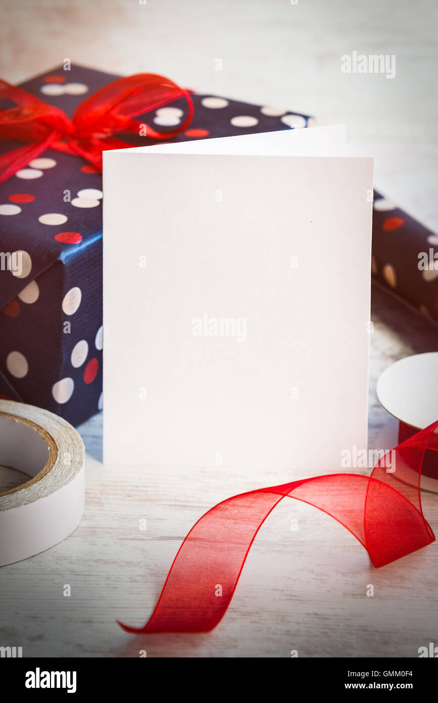 Empty greeting white card. Wrapped gift and wrapping materials over a ...