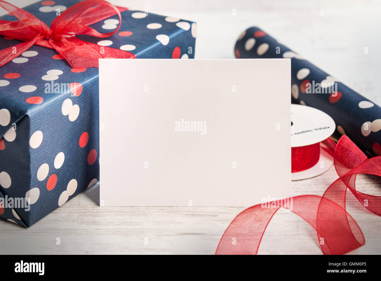 Empty greeting white card. Wrapped gift and wrapping materials over a ...