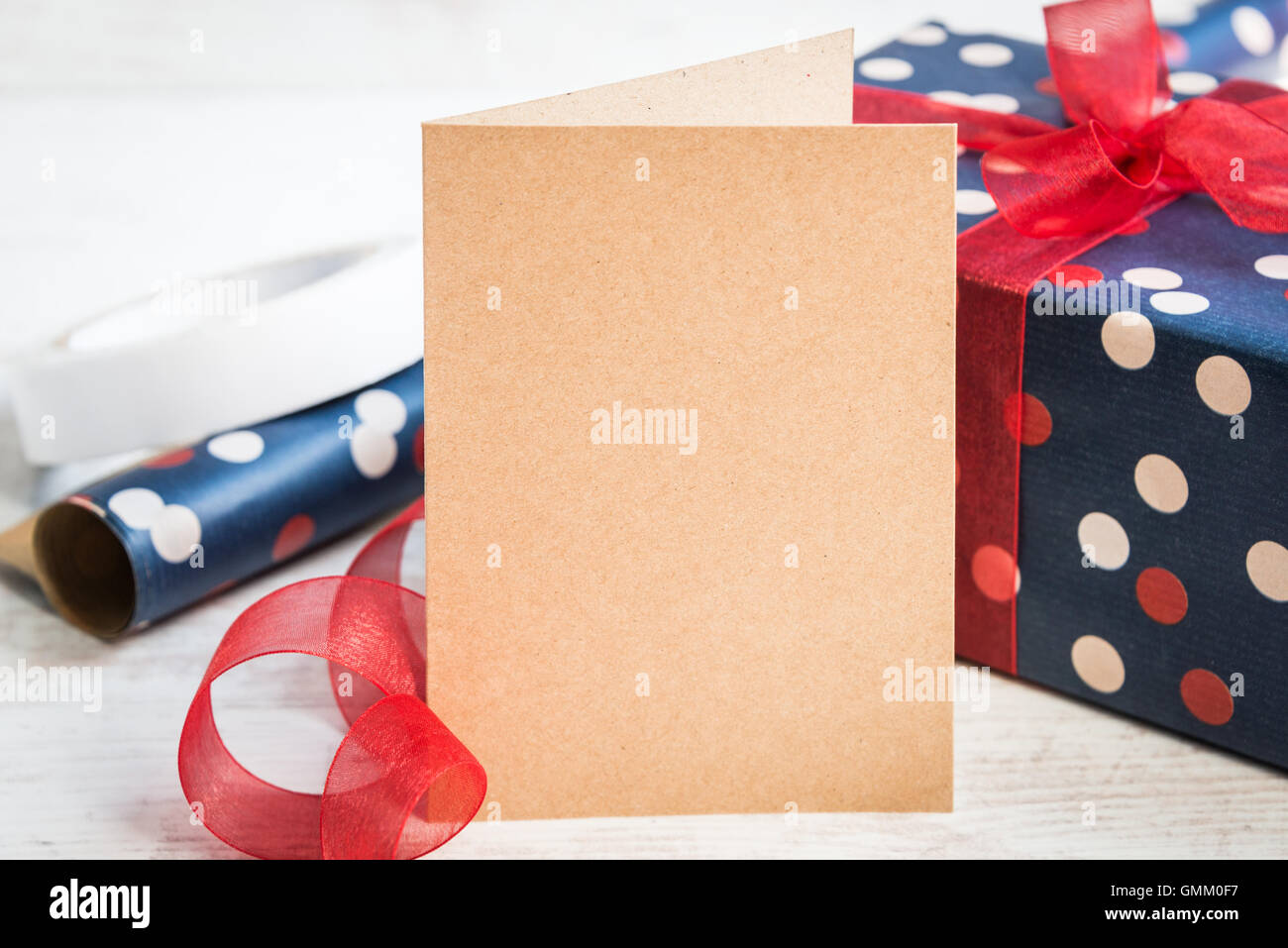 Empty greeting kraft card. Wrapped gift and wrapping materials over a ...