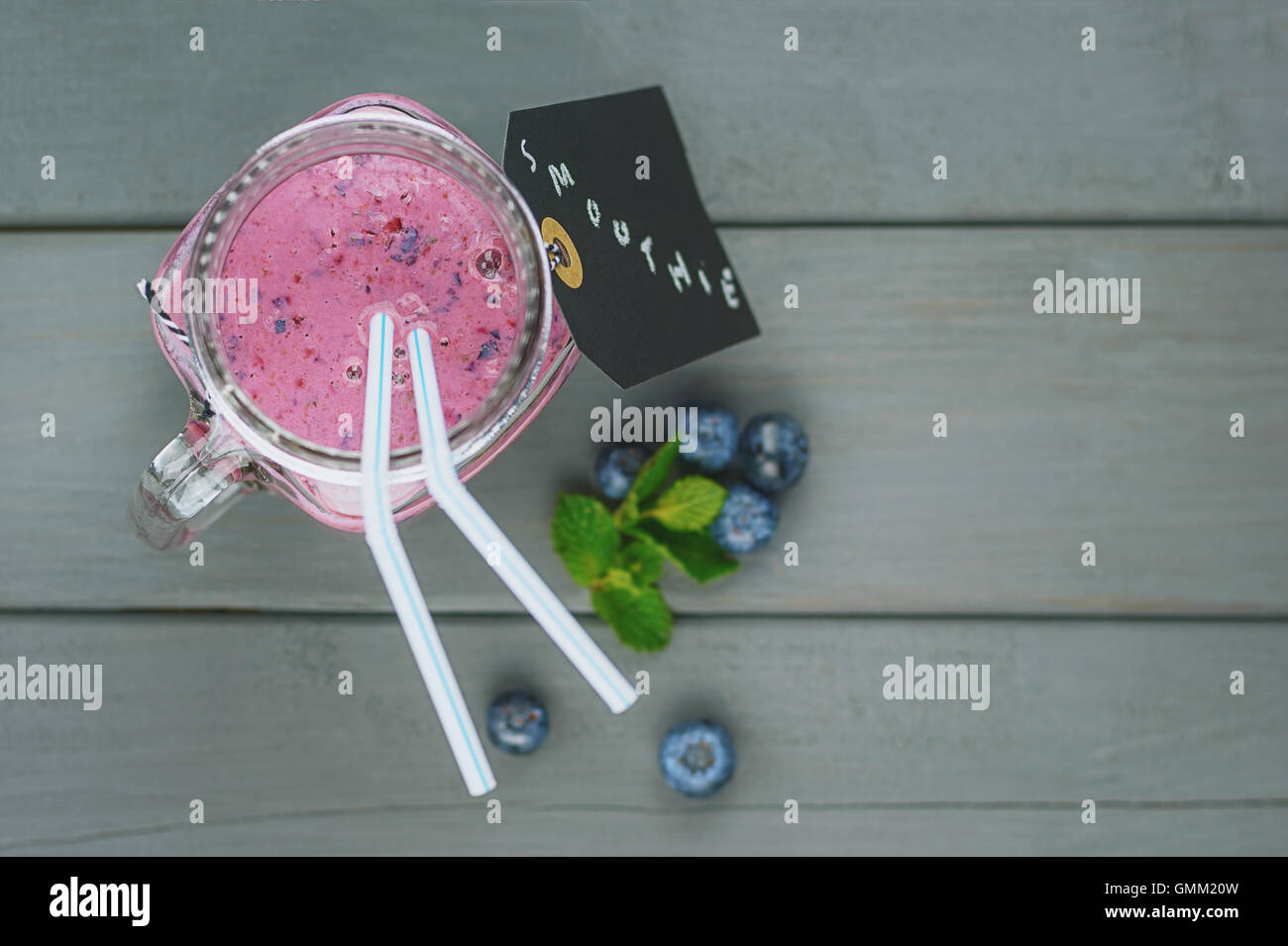 Cup of blueberry smoothie with a signed label on a table, on which lay ...