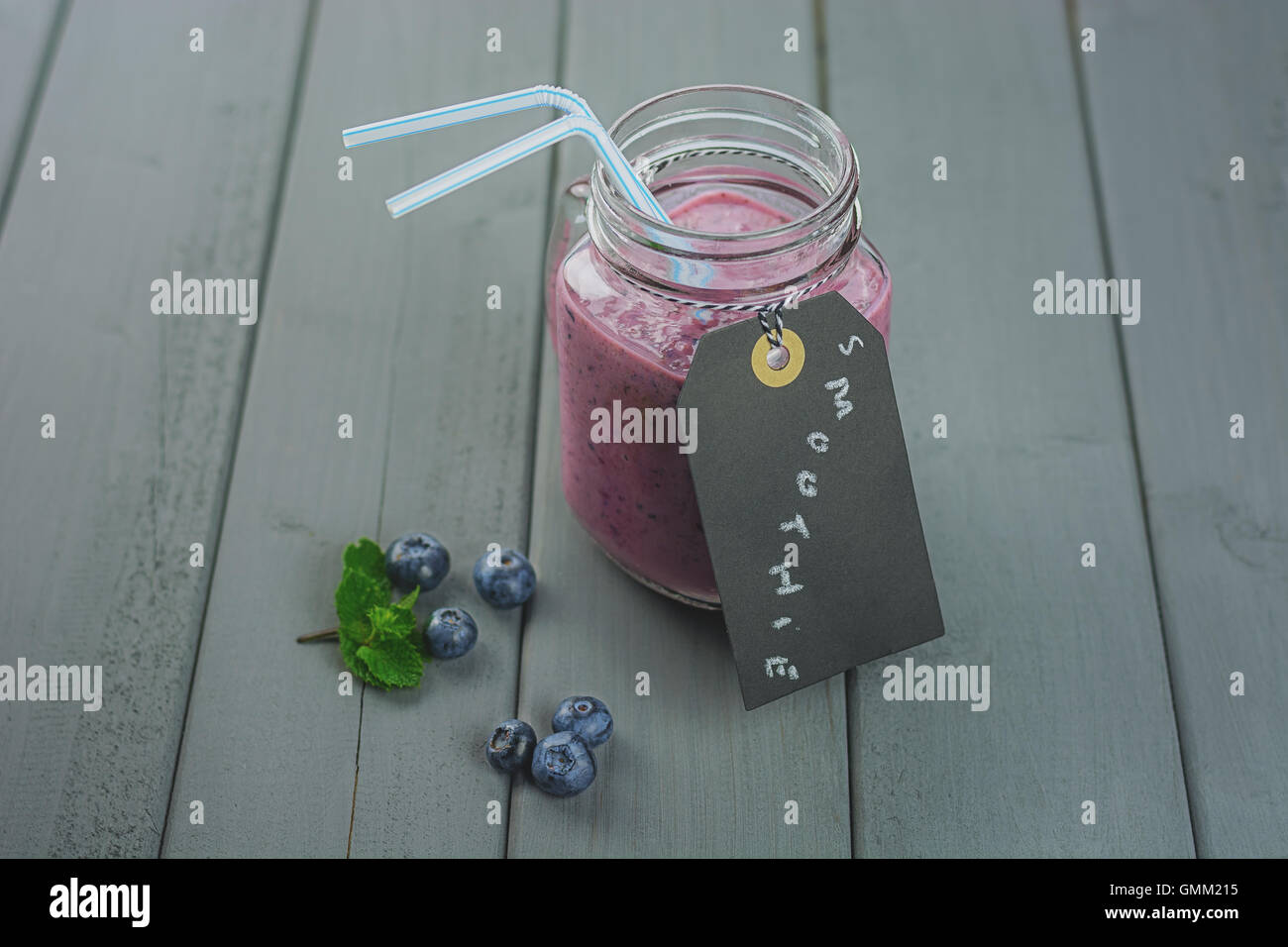 Cup of blueberry smoothie with a signed label on a table, on which lay ...