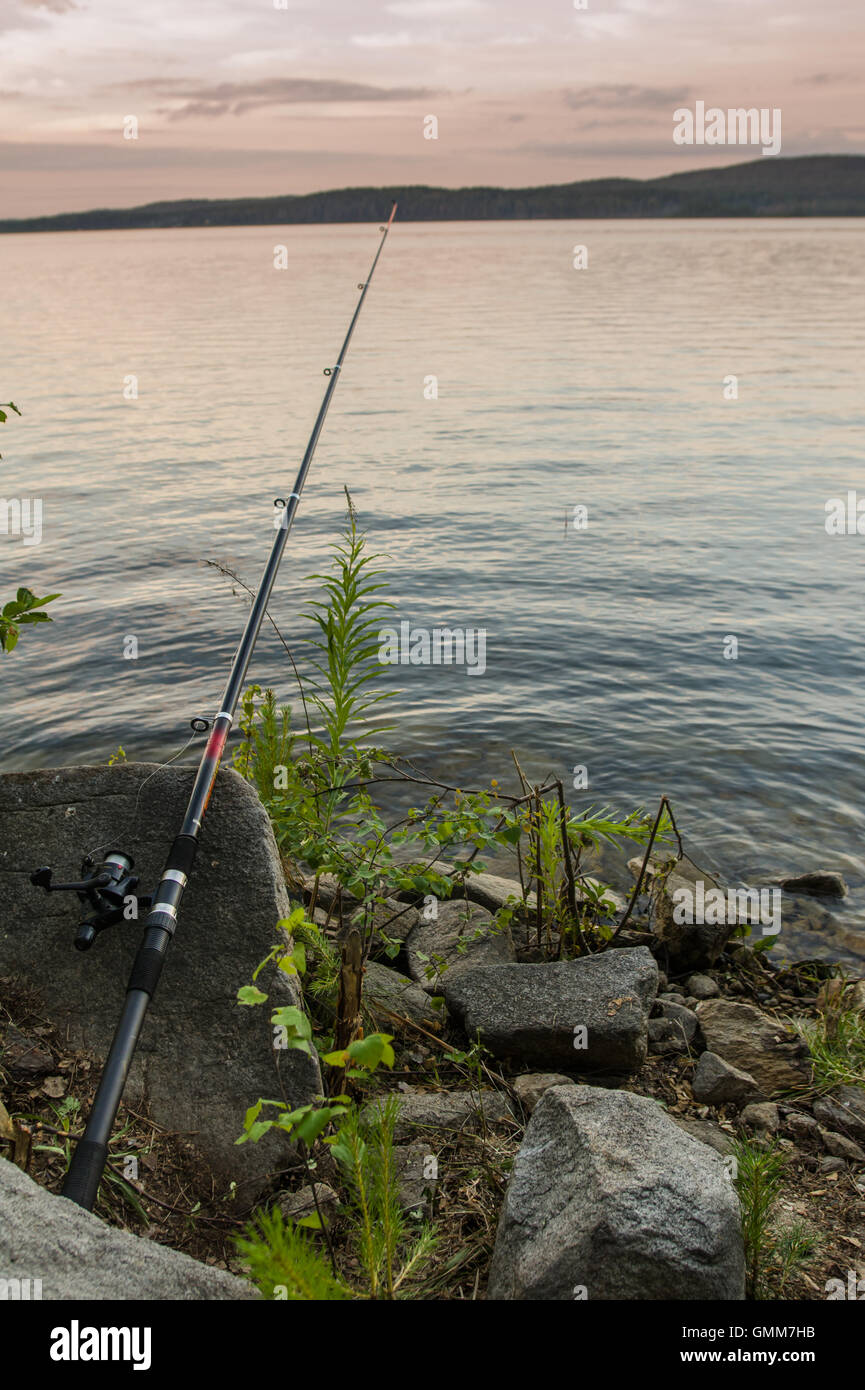 long fishing rod lying on the rocks by the lake Stock Photo - Alamy