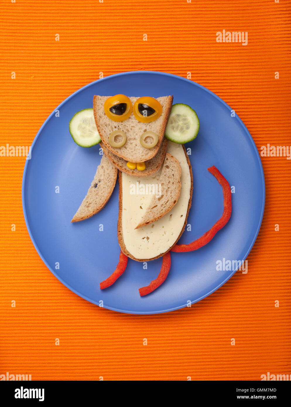 Amusing monkey made of bread, cheese and vegetables on plate and fabric ...