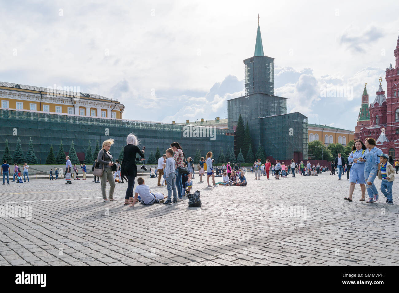 Tourists resting on the cobblestones of Red Square. Kremlin wall ...