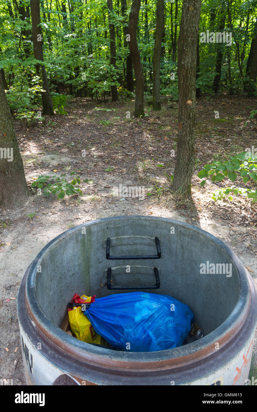 Summer forest with an opened rubbish bin, to collect all the rubbish ...