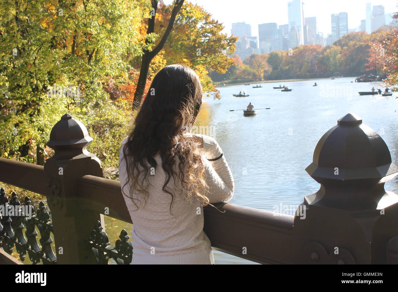 A woman looking over a wooden rail at the lake and the sailing boats ...