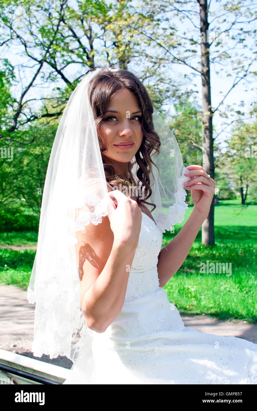 beautiful young bride sitting on a park bench Stock Photo - Alamy