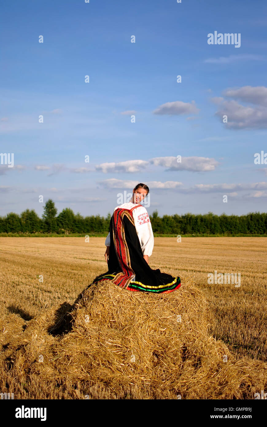 girl in traditional Russian costume sitting on a haystack Stock Photo ...