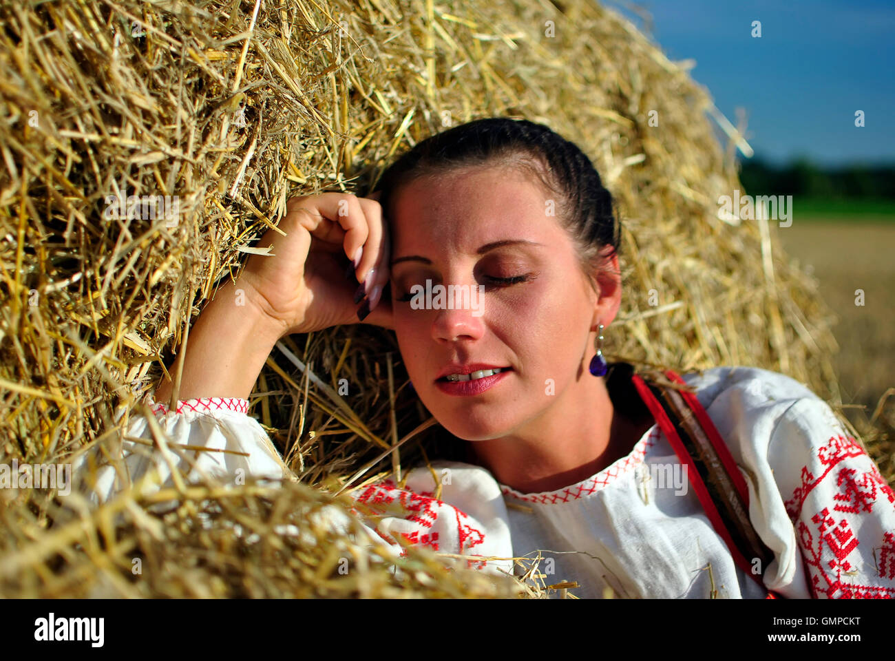 girl in traditional Russian costume resting on a haystack Stock Photo ...