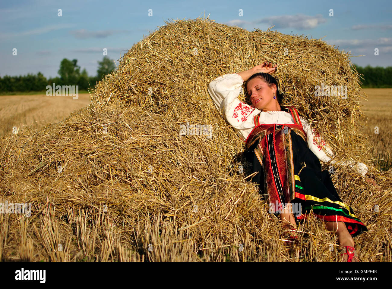 girl in traditional Russian costume resting on a haystack Stock Photo ...