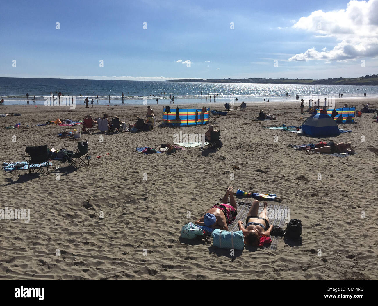 People enjoying the warm weather on Carne beach in Cornwall Stock Photo ...
