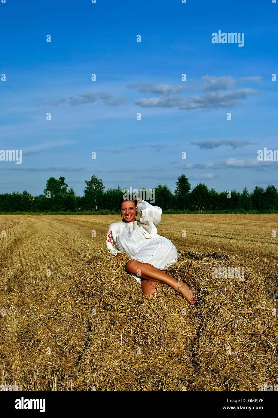 girl in traditional Russian costume sitting on a haystack and smiling ...