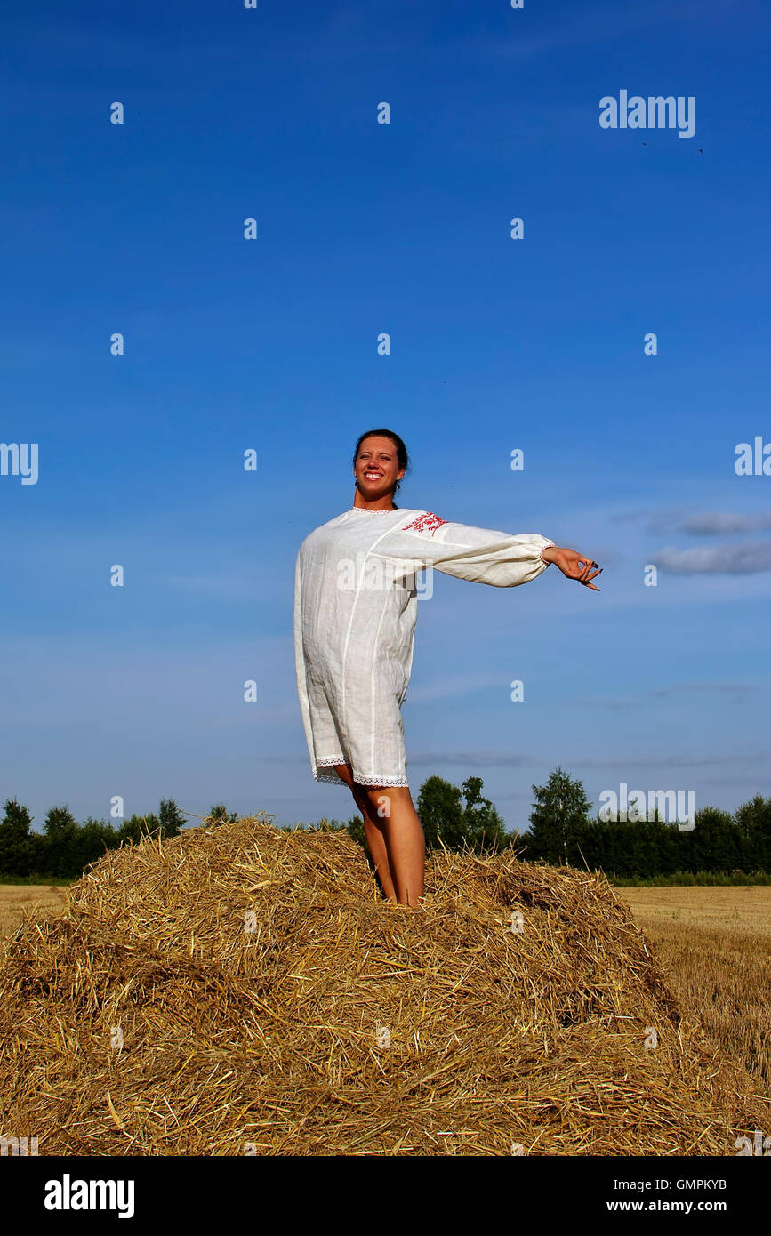girl in traditional Russian costume standing on a haystack Stock Photo ...