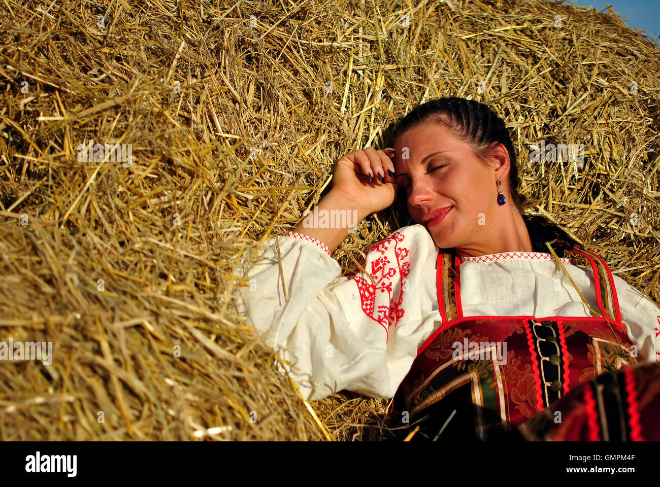 girl in traditional Russian costume resting on a haystack Stock Photo ...