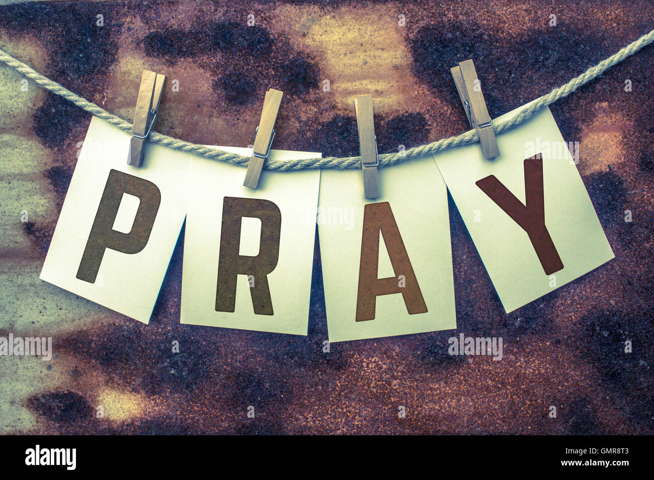 The word PRAY stamped on card stock hanging from old twine and clothes ...