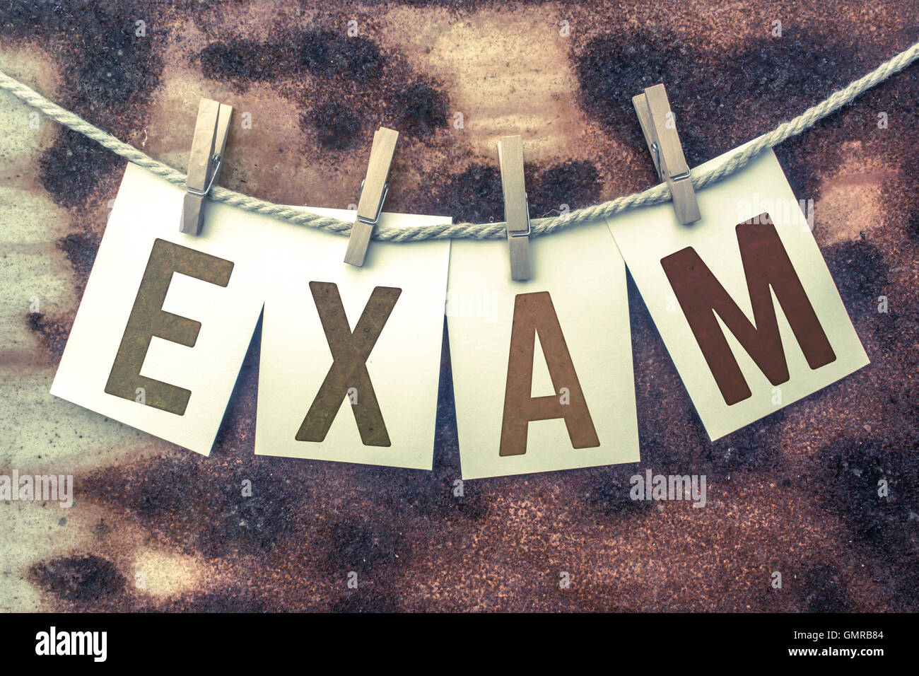 The word "EXAM" stamped on cards and pinned to an old piece of twine ...