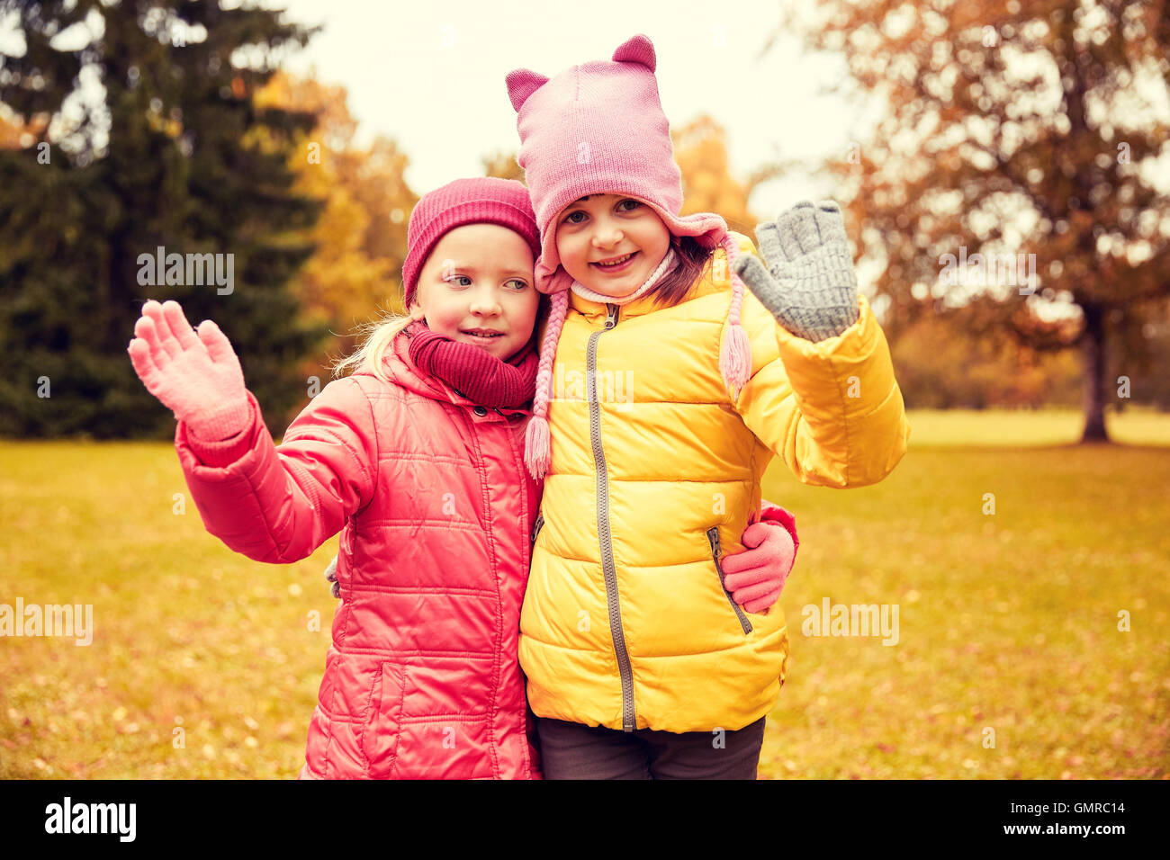 two happy little girls waving hand in autumn park Stock Photo - Alamy