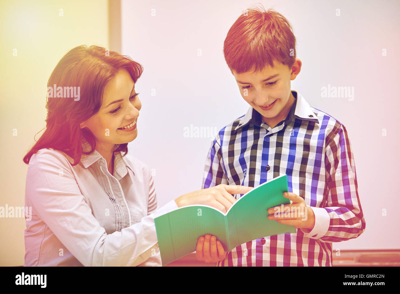 school boy with notebook and teacher in classroom Stock Photo - Alamy