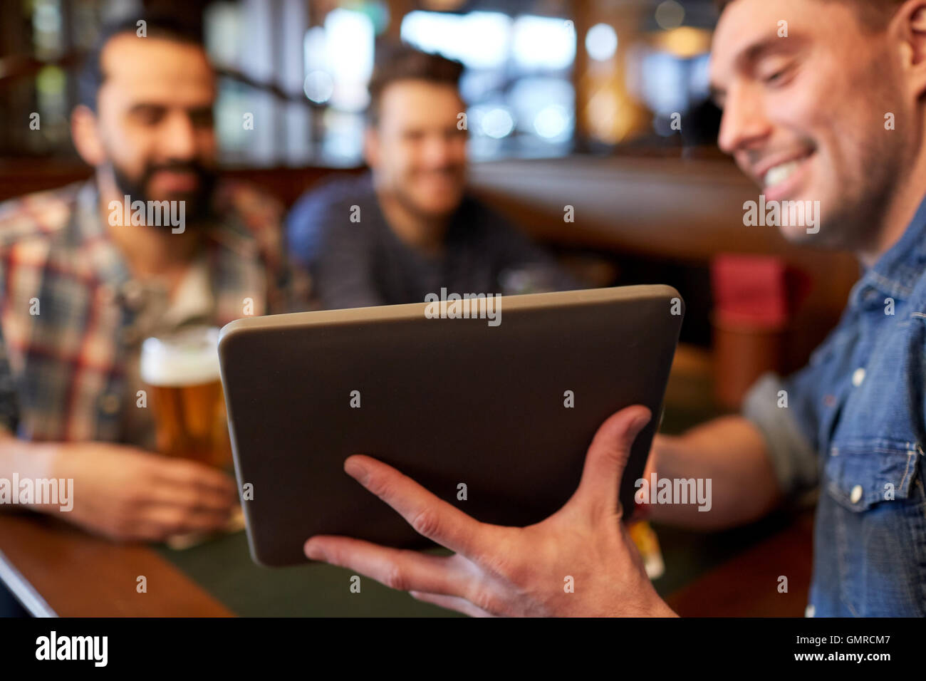 male friends with tablet pc drinking beer at bar Stock Photo - Alamy