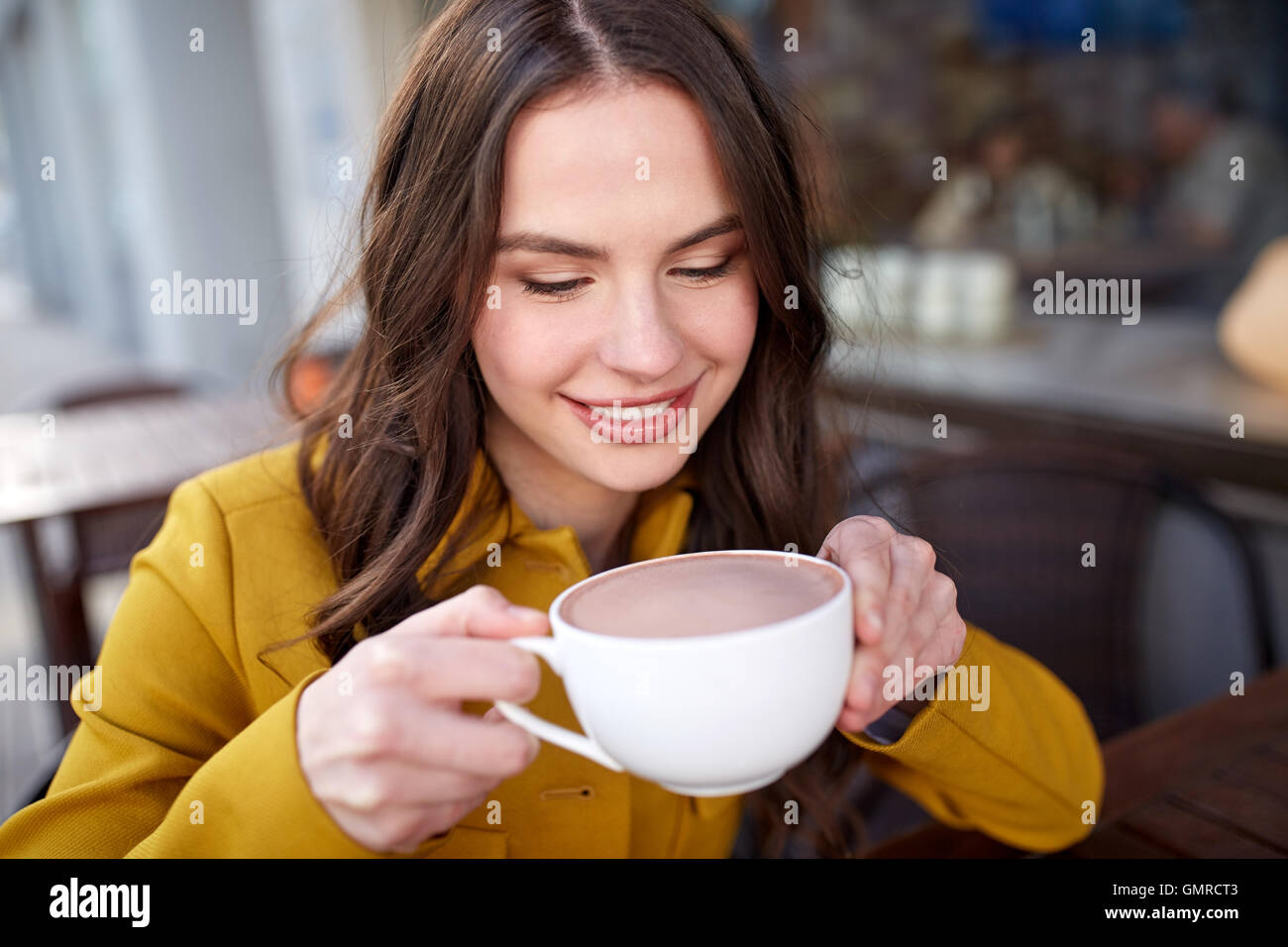 happy woman drinking cocoa at city street cafe Stock Photo - Alamy