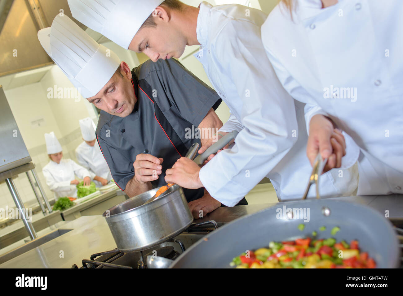 Chef checking trainee's pan of food Stock Photo - Alamy