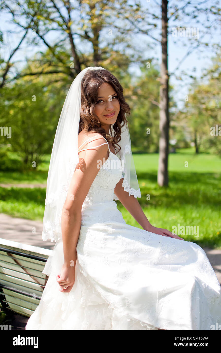 beautiful young bride sitting on a park bench Stock Photo - Alamy