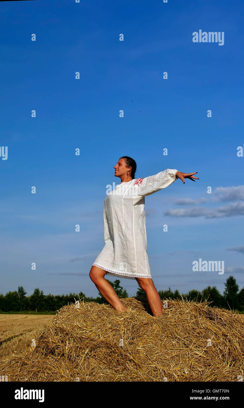 girl in traditional Russian costume standing on a haystack Stock Photo ...