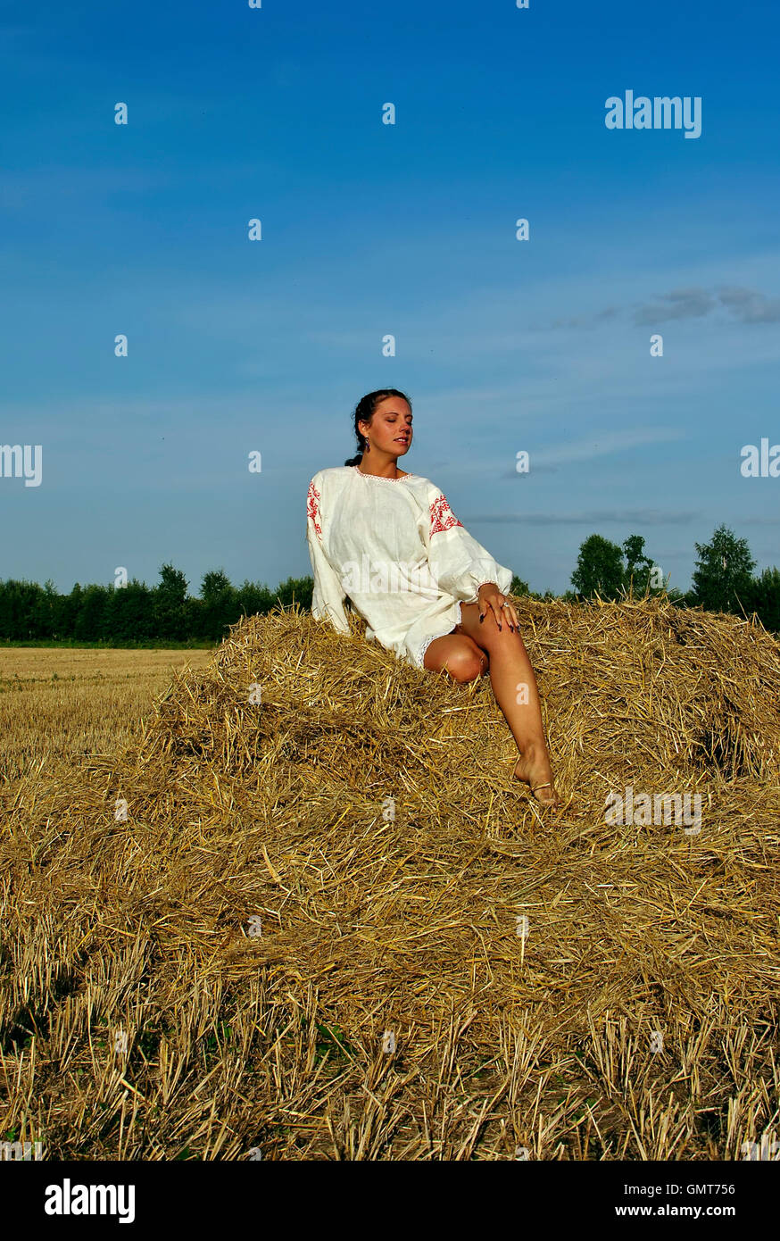 girl in traditional Russian costume sitting on a haystack Stock Photo ...