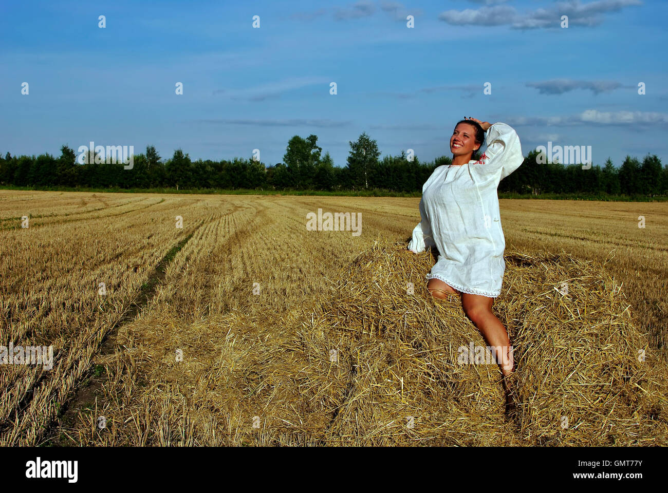 girl in traditional Russian costume sitting on a haystack and smiling ...