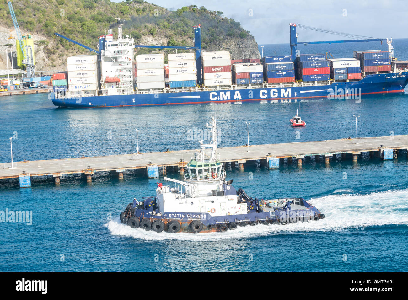 A large tugboat along a huge, loaded CMA CGM freighter in St Maarten ...