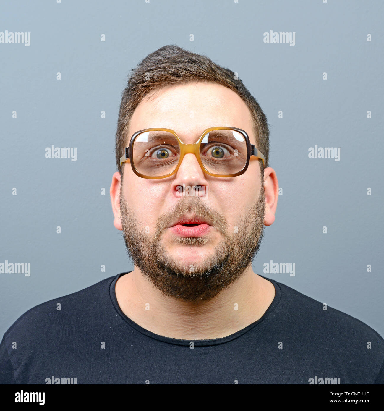 Portrait of a confused chubby geek against gray background Stock Photo ...