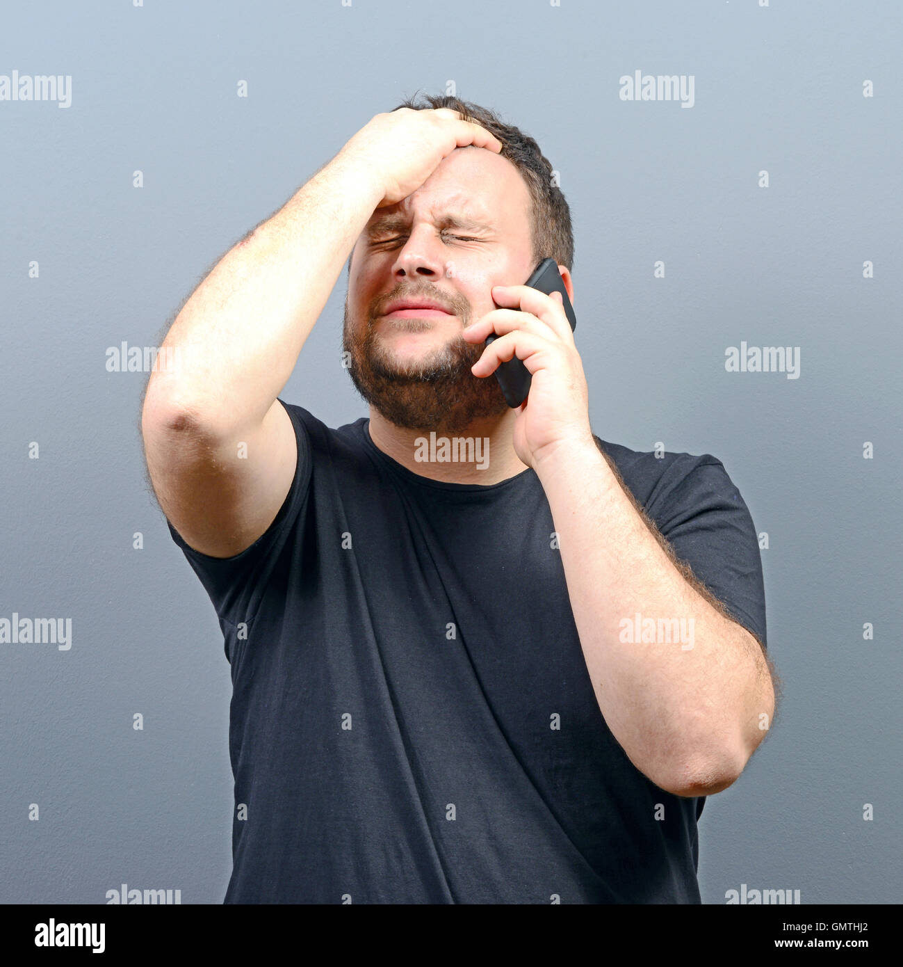 Portrait of a man slaping his forehead while talking on cellphone ...