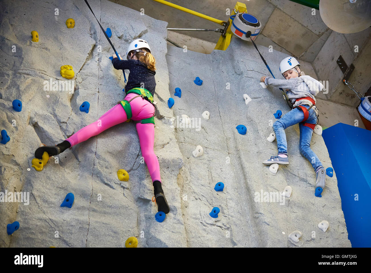 Two girls climbing to amusement park on blue wall Stock Photo - Alamy