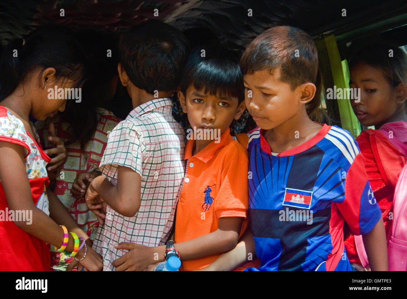 A group of young Cambodian children are crowded into a mini van at an ...