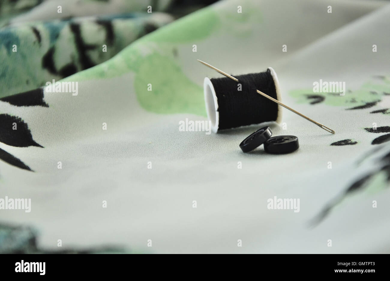 Needle, thread and two buttons on a green colored cloth, Sewing themes ...