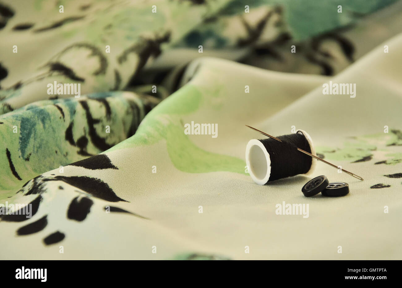 Needle, thread and two buttons on a green colored cloth, Sewing themes ...