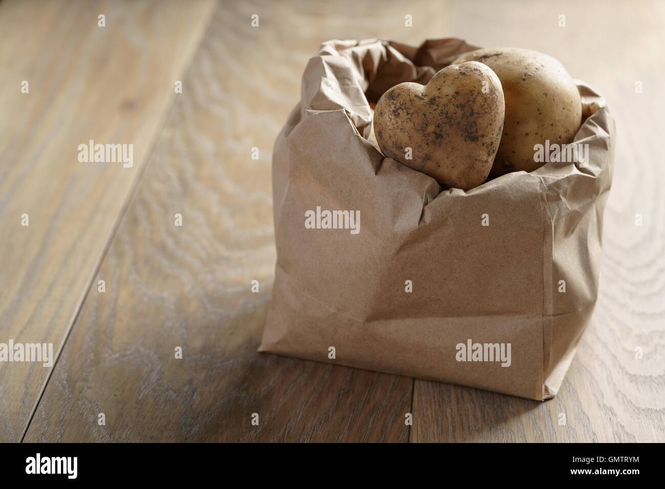 fresh potatoes in kraft paper bag on oak table Stock Photo - Alamy