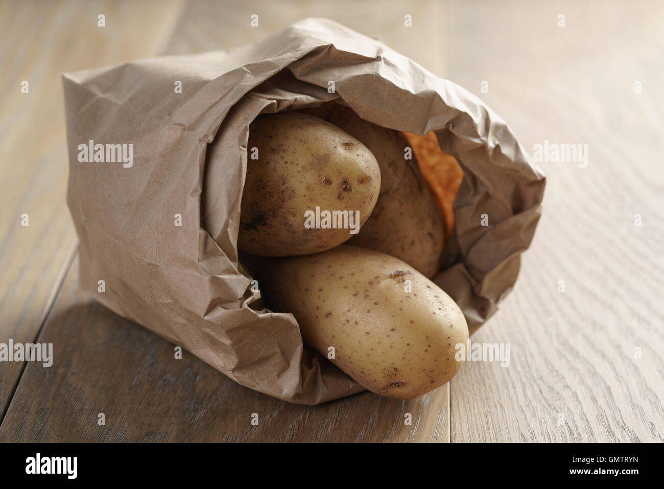 fresh potatoes in kraft paper bag on oak table Stock Photo - Alamy